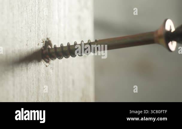 Close-up yellow self tapping screw screwing into wall surface. Macro ...