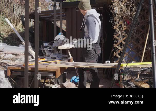 Man working outdoors on a carpentry project with a wooden boards and a ...