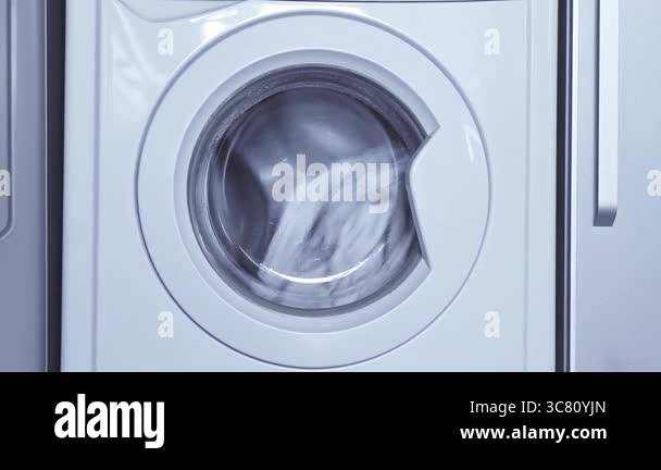 Washing machine in operation, washing light clothes, drum rotating ...