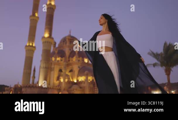 Elegant woman in flowing attire posing in front of the illuminated ...