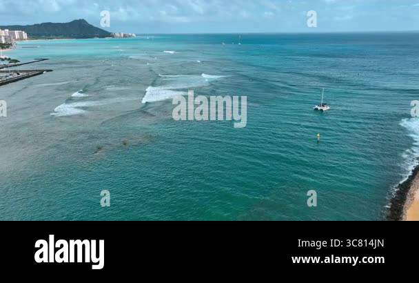 Waves rolling slow to the dam at the coast of Honolulu. Boat floats to ...