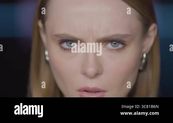Close-up of a woman frowning with intense eye contact and vibrant ...