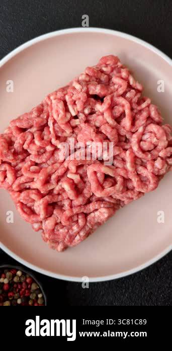 Stuffing or ground raw beef or pork with salt and spices on a black ...
