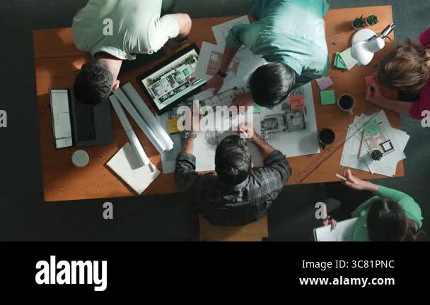 Top view of civil engineer team holding blueprint and standing at table ...