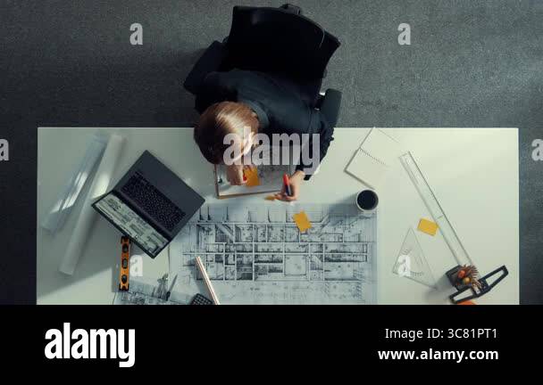 Aerial view of architect drawing while working at laptop. Top down view ...
