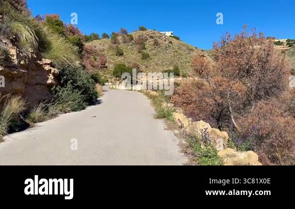 There is a tranquil walking path, encircled by gentle hills and lush ...