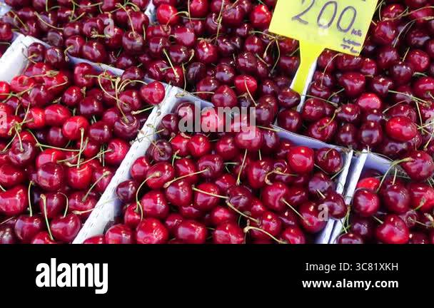 Bright red cherries displayed for sale at a local market stall Stock ...