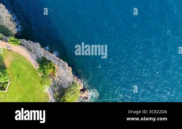 Direct overhead drone shot captures jagged rocky cliffs meeting deep ...