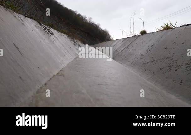 Murky water streaming through concrete drainage channel alongside ...