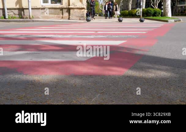 Traffic crossing urban intersection, people walking alongside vehicles ...
