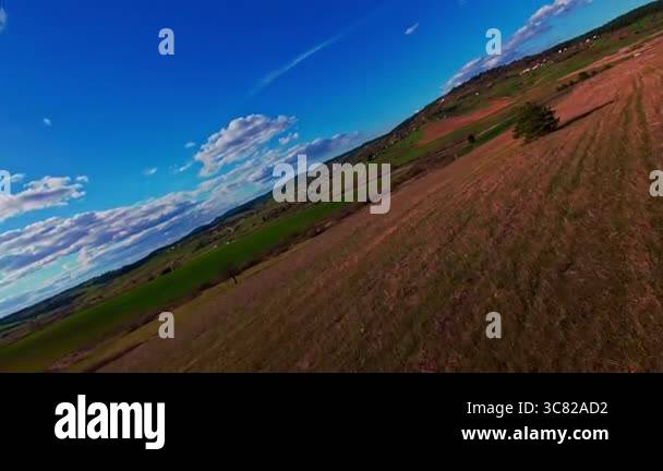Vertical video FPV drone view banking over vibrant green fields and ...