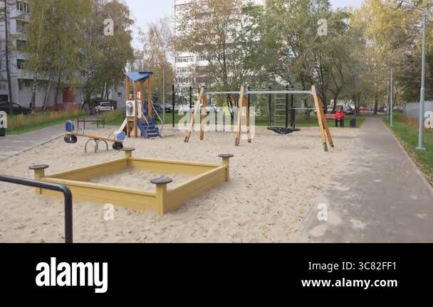 Sandy playground with sandbox swings slides and seesaw near paved ...
