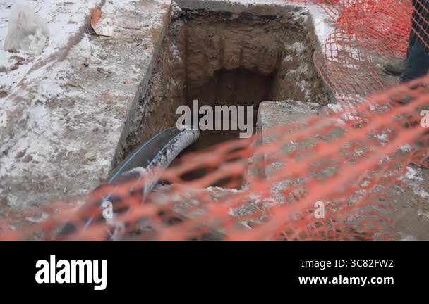 Long rubber hose disappears into open sewer pit during routine ...