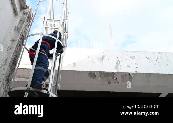 worker in a helmet and protective suit climbing the metal ladder Stock ...