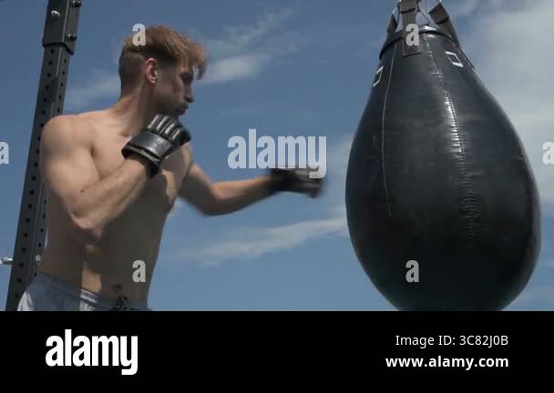 Professional fighter practicing boxing, hitting punching bag on sports ...