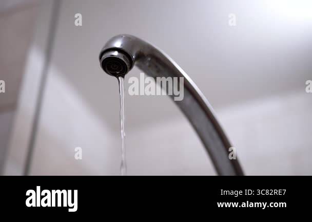 A steady stream of water flows from a chrome faucet against a softly ...