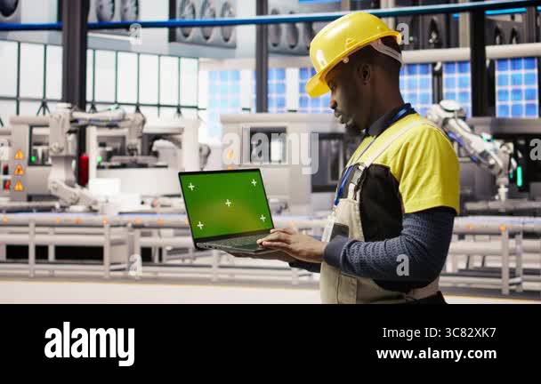Engineer in smart factory using green screen laptop to analyze IoT ...