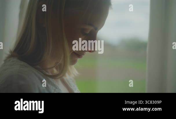 Nostalgic woman gazing out the window, deep in thought, and ...