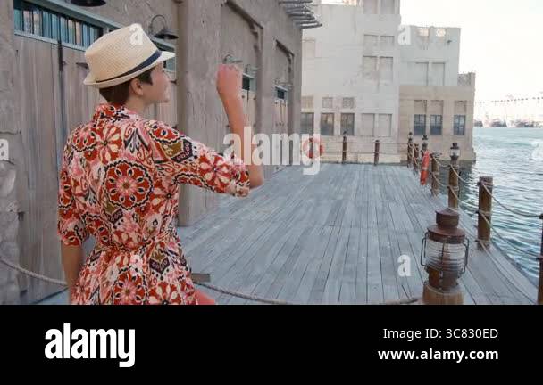 Young woman in ethnic dress and hat exploring Al Seef Park in Dubai ...