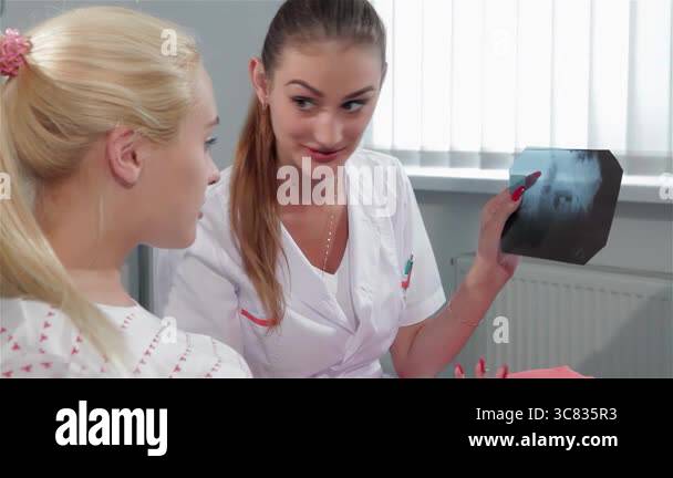 A skilled brown-haired female dentist engages with her patient ...