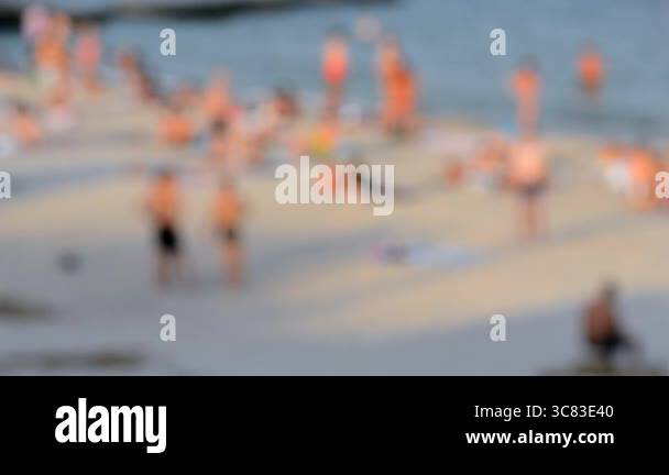 Many people on beach by sea on summer evening. Men and women in bathing ...