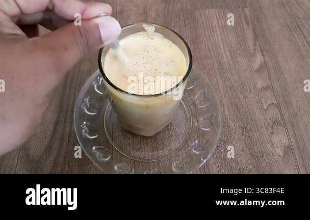 A glass of Teh Talua being stirred, a traditional Minangkabau egg tea ...