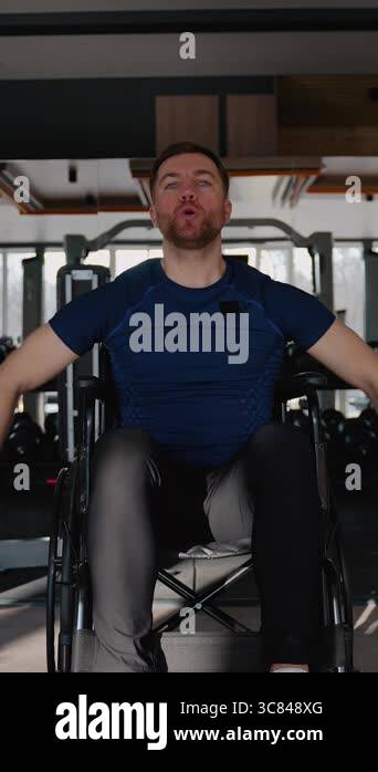 Man In Wheelchair Performing Lat Pulldown Exercise In Gym Focusing On