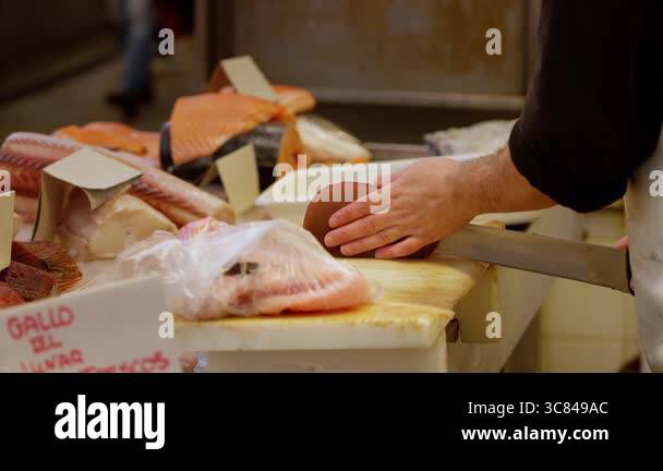 Fishmonger preparing tuna steak, slicing fresh fish on cutting board at ...
