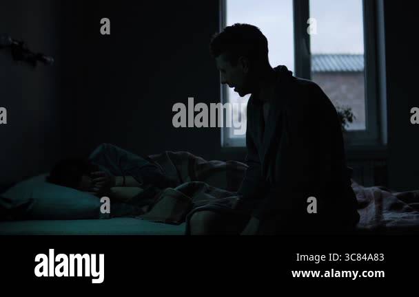 Man screams and gestures at crying woman in dim bedroom. Domestic ...