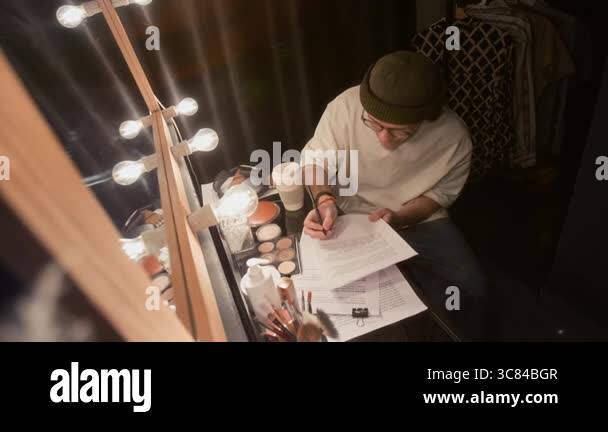 High angle shot of man making notes in his printed out stand-up script ...