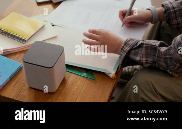 Child reaching to activate smart speaker while doing his homework ...