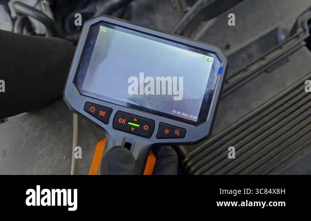 Mechanic inspecting engine with borescope camera, diagnostic tool ...