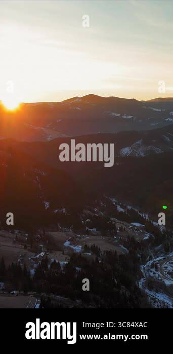 Golden sunrise over a snowy mountain valley, warm morning glow casting ...