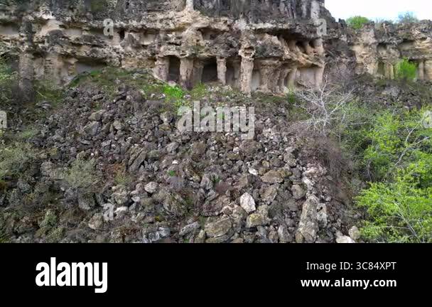 Eroded cliffside with natural stone columns and small caves, part of ...