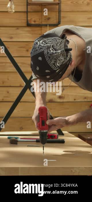 manual assembly of a garden table handyman drills a hole in the table ...