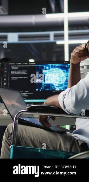 Vertical video Data center computer scientist in wheelchair using AI node tree software to ...