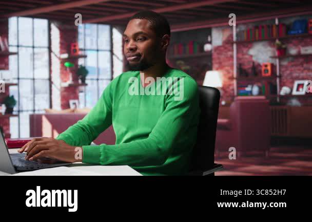 Black teleworker at home desk opening laptop to edit documents and solve daily tasks, updating ...