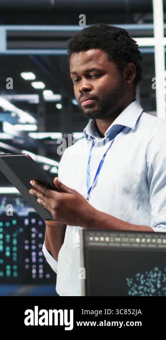 Vertical video Data center technician using tablet to do node tree programming, optimizing ...