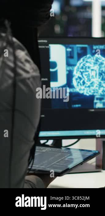 Vertical video Data center engineer in wheelchair and colleague oversee automated tasks using ...