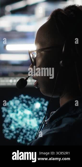 Vertical video Data center employee uses audio headset and visual programming dashboard to ...