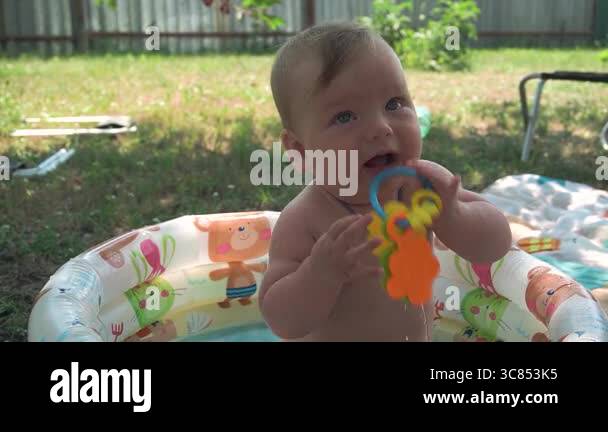 cute blue-eyed baby with a cross on his neck interestedly examines a ...