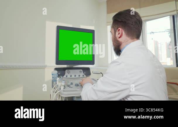 A cheerful male doctor skillfully operates an ultrasound scanner ...