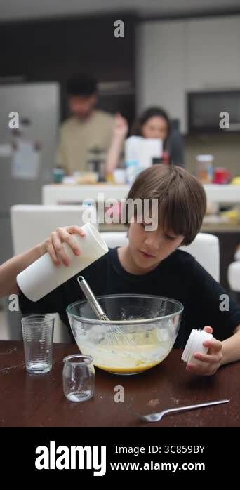 In a lively kitchen, a child mixes ingredients in a bowl, surrounded by ...