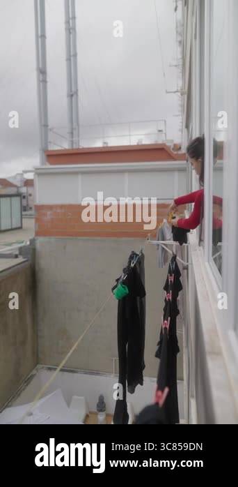 On a cloudy day, a person hangs freshly washed clothes outside a window ...