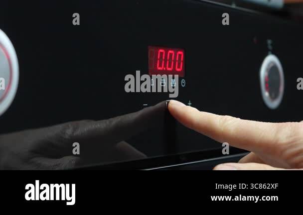 Close-up of a hand adjusting the digital display of a microwave oven ...