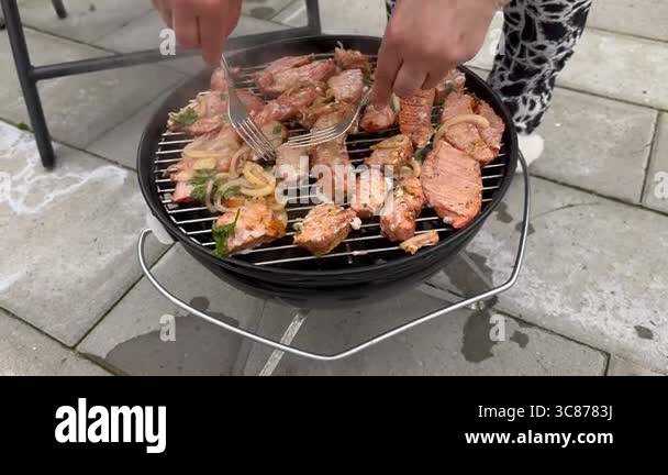 Woman basting meat on barbecue with fresh herbs, Beef grilling picnic ...