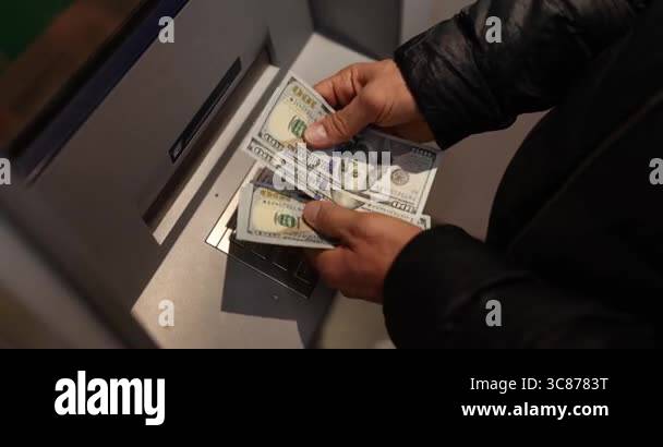Man counts dollar bills standing near ATM machine on street at night ...