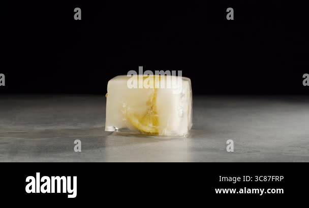 Lemon in an ice cube, close-up. Time lapse of the ice melts and a half ...