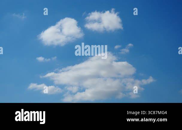 Fluffy white clouds drift serenely in a brilliant azure expanse as ...