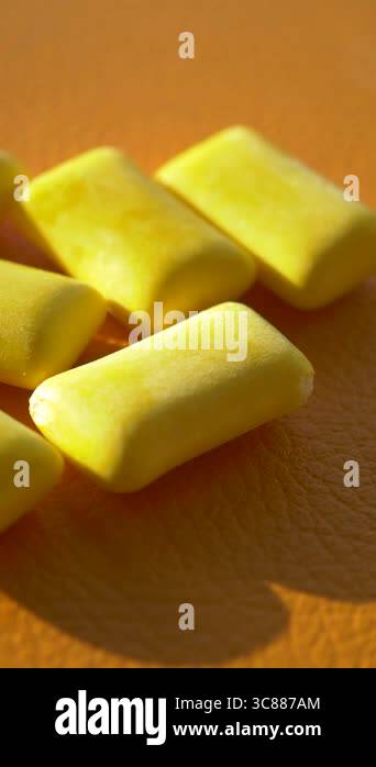 Close-up of yellow chewing gum pieces on an orange surface Stock Video ...
